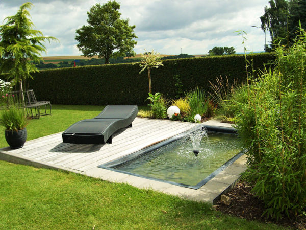 Ein Platz am Wasser mit Gartenliege und formalem Wasserbecken ...